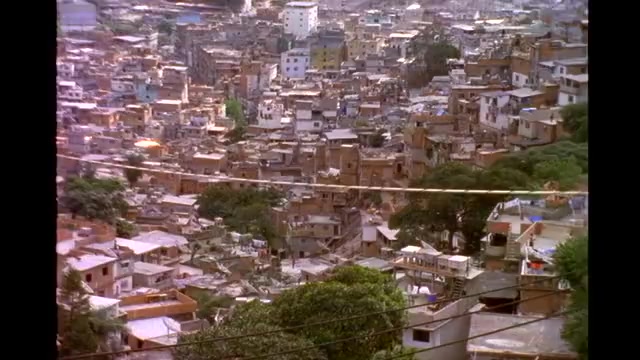 Slums of Rio de Janeiro, favallas, on hillside, tilt up to high rise ...